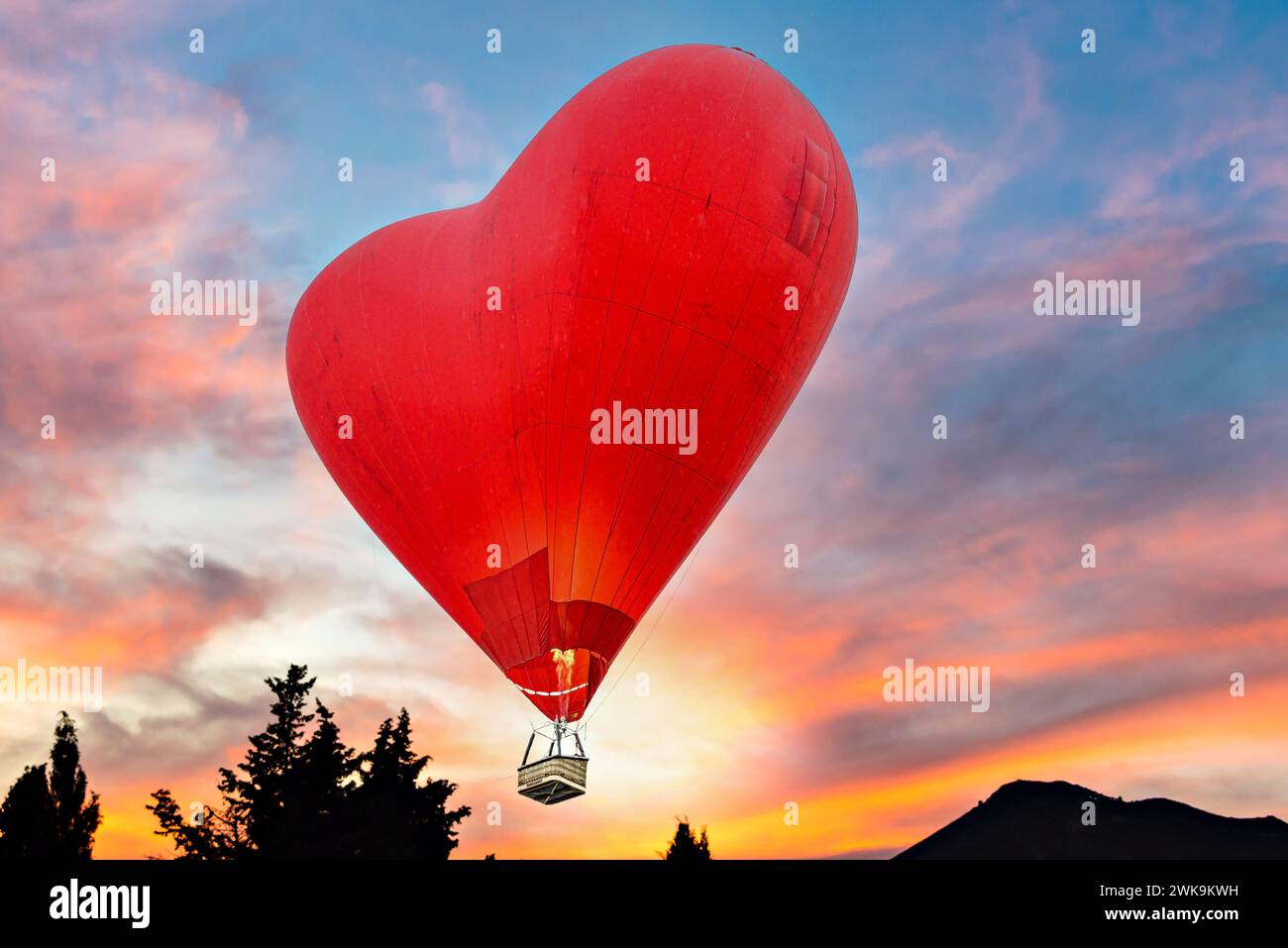 Red heart shaped hot air balloon flying over sunset sky Stock Photo - Alamy