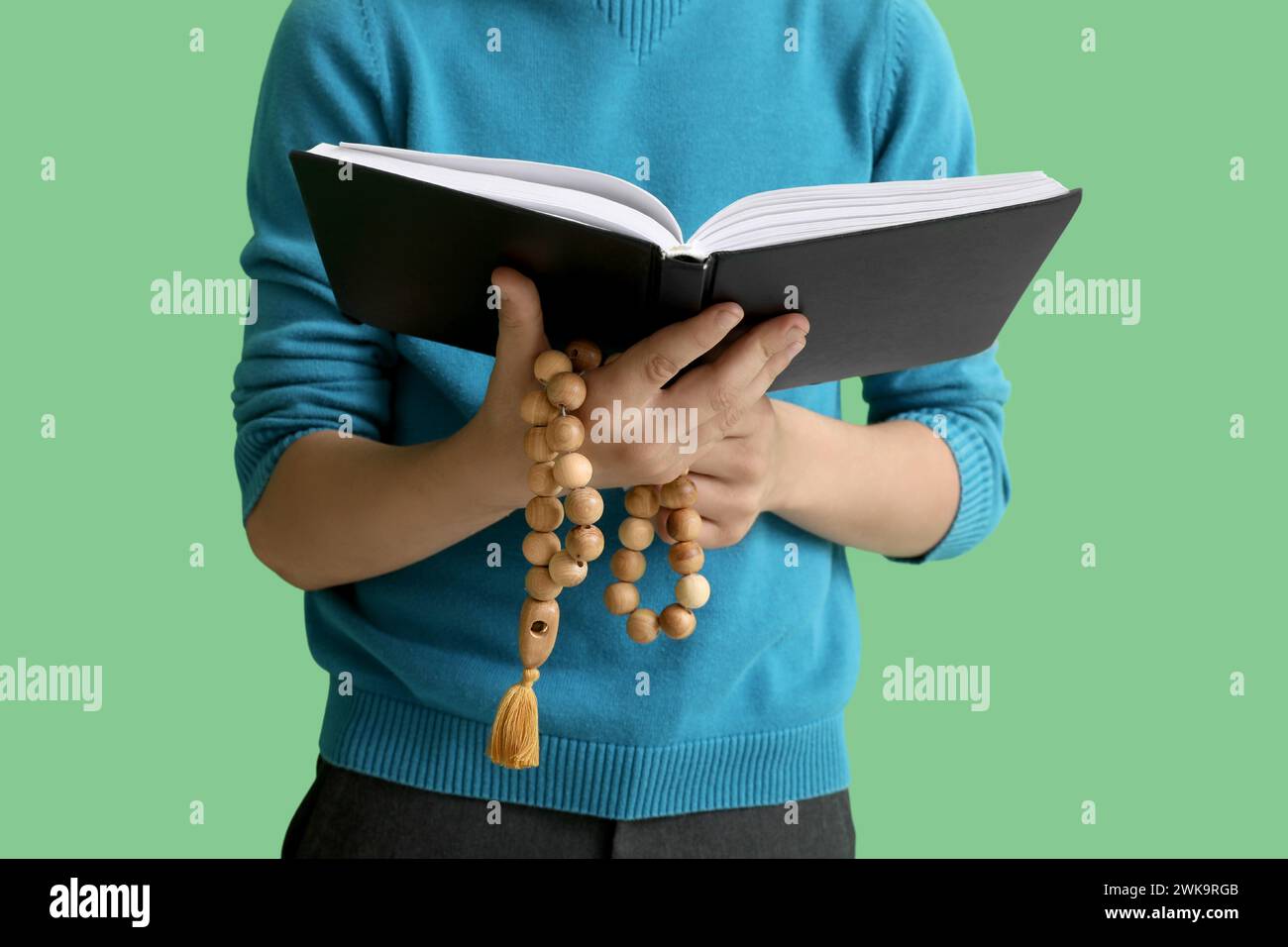 Little Muslim boy with Quran and praying beads on green background ...