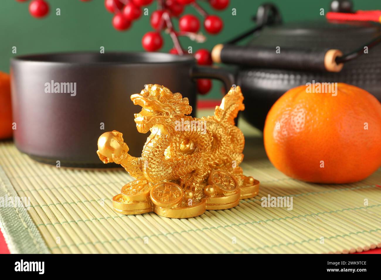 Traditional tea setup with golden dragon figurine and mandarin on green ...