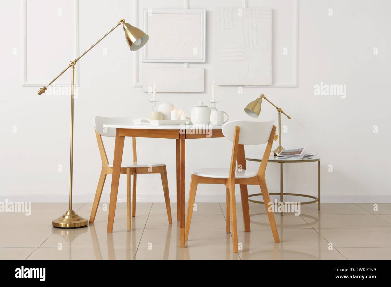 Interior of light room with dining table, paintings and golden lamps ...