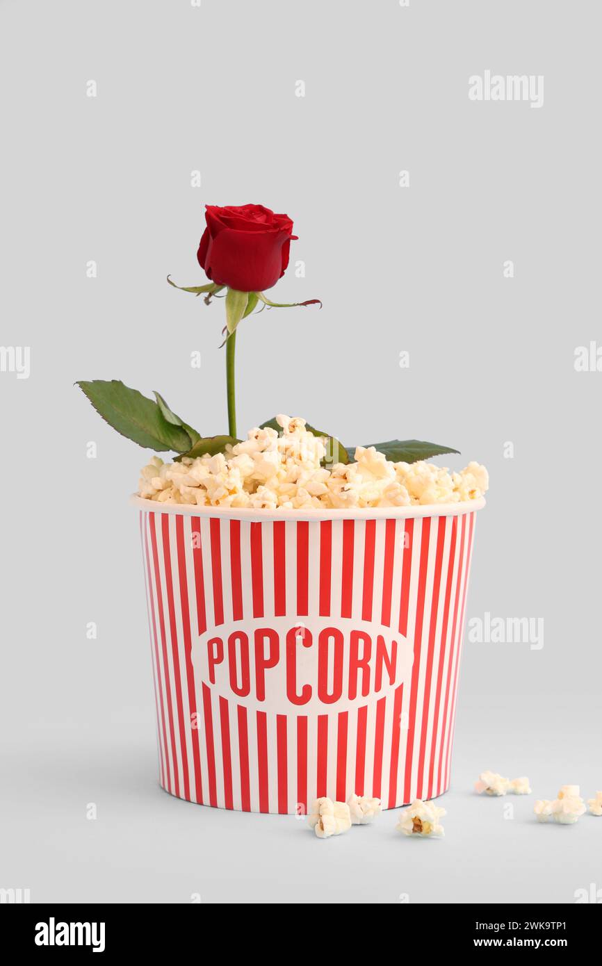 Bucket of popcorn with beautiful rose on blue background. Valentine's ...