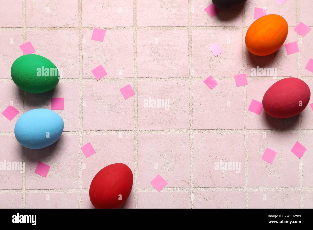composition-with-painted-easter-eggs-and-confetti-on-pink-tile