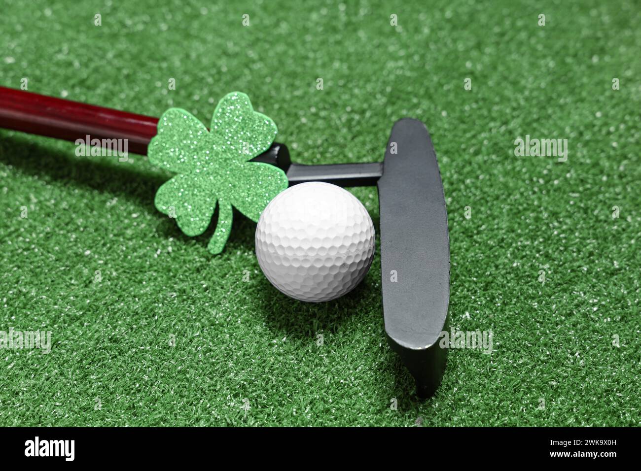 Golf club, ball and clover on green grass background. St. Patrick's Day ...