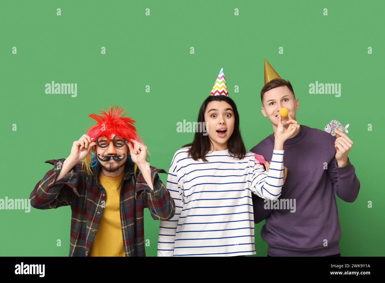 Young shocked friends in funny disguise with paper fish on green ...