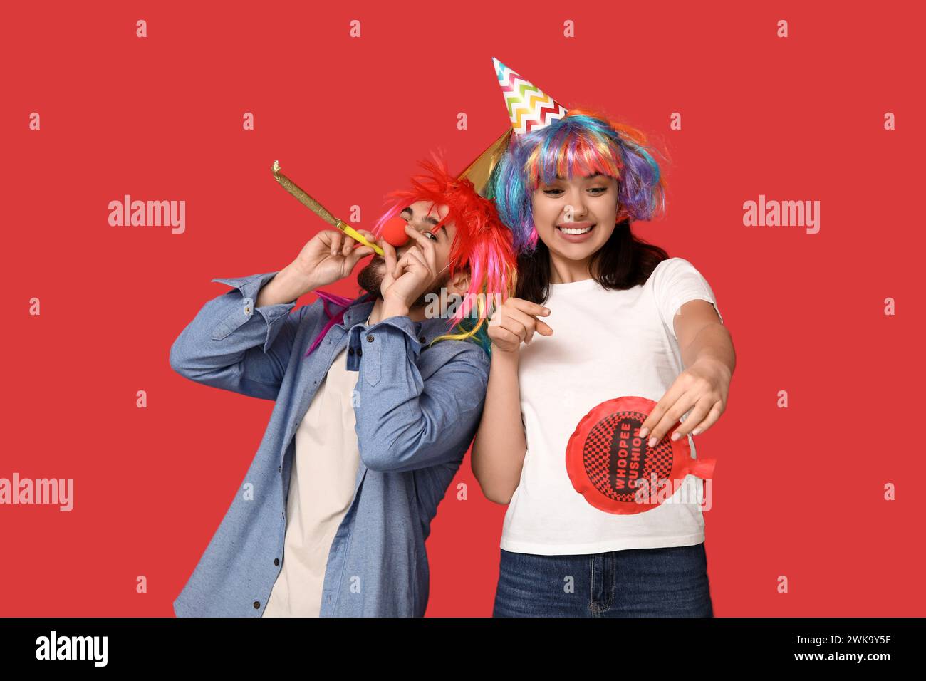 Young friends in funny disguise with party whistle pointing at whoopee ...