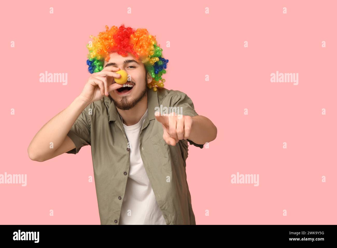 Handsome young man in funny disguise pointing at viewer on pink ...