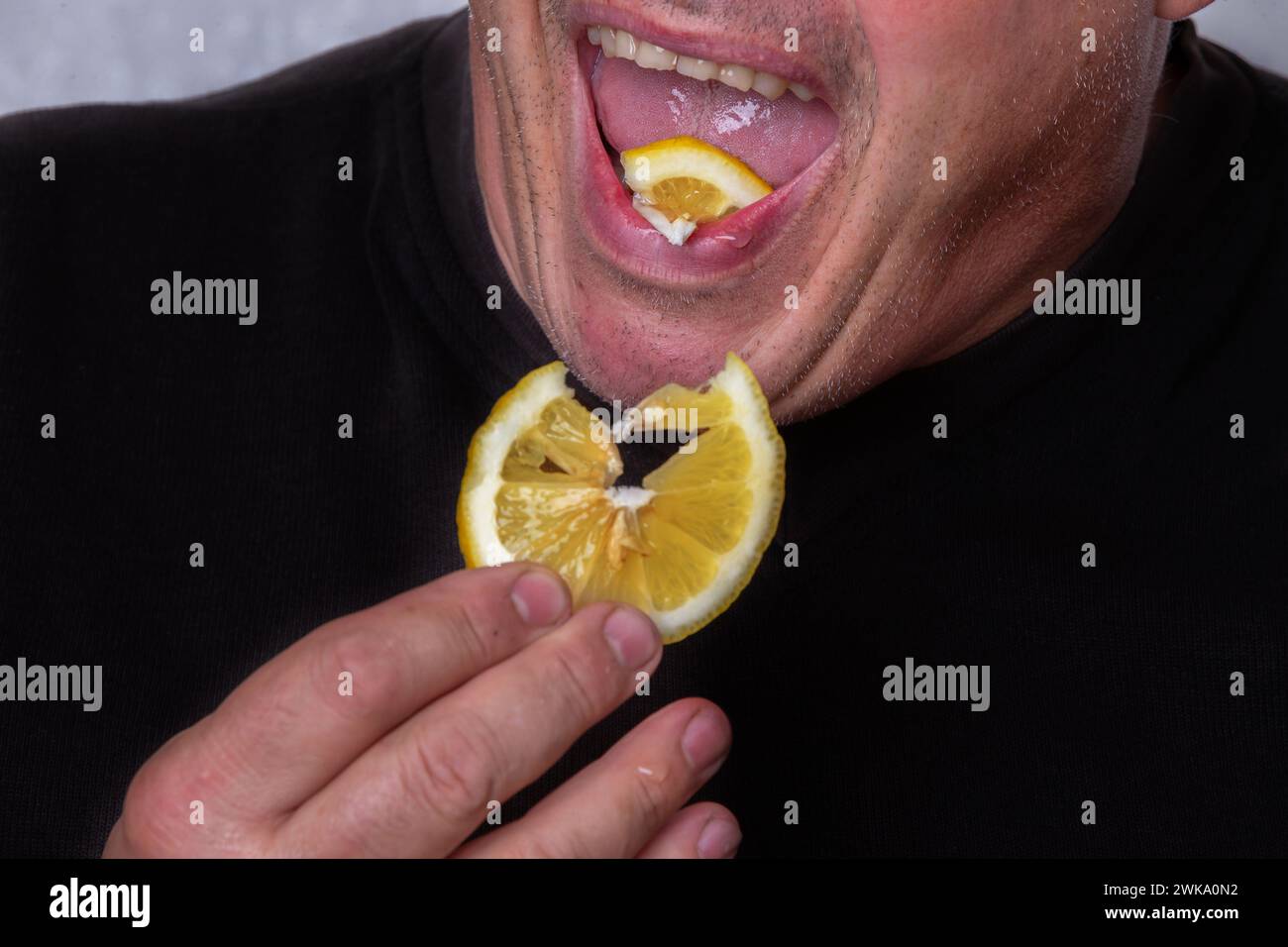 An unrecognizable man eats a sour lemon Stock Photo - Alamy
