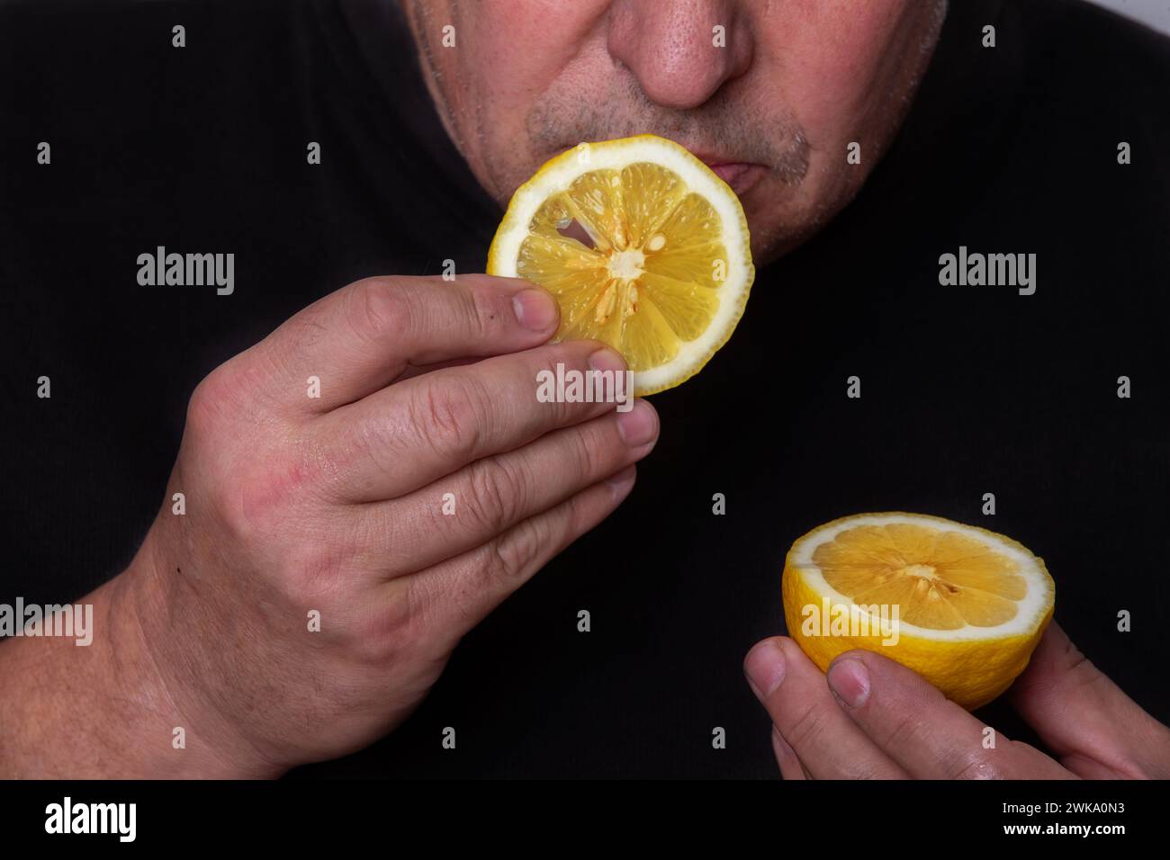 An unrecognizable man eats a sour lemon Stock Photo - Alamy