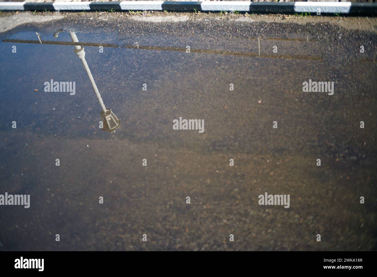 The reflection of old fashioned street lamp post in rain puddle on an ...