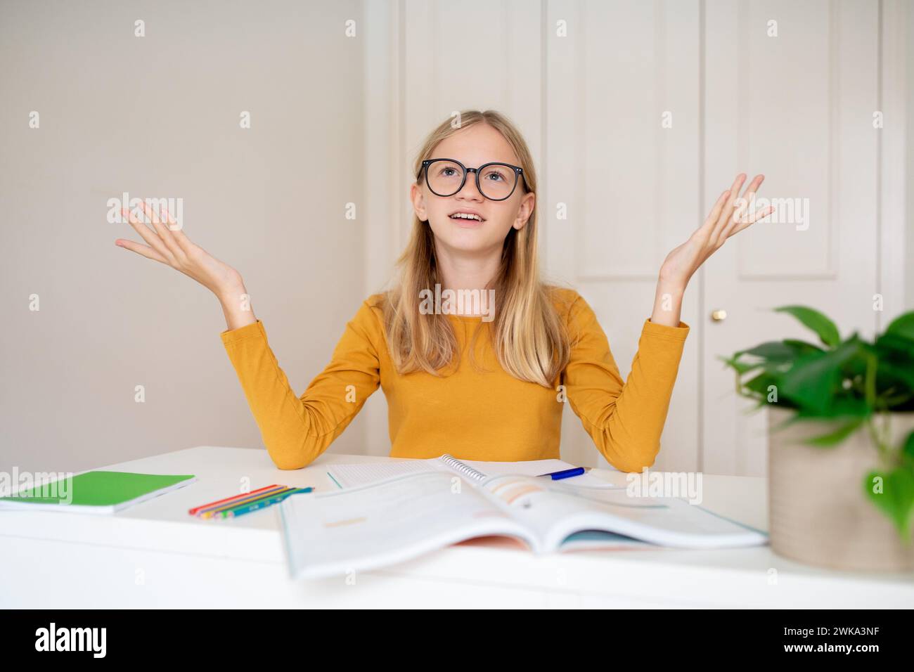 Confused teen girl studying with books at home and raising her hands ...