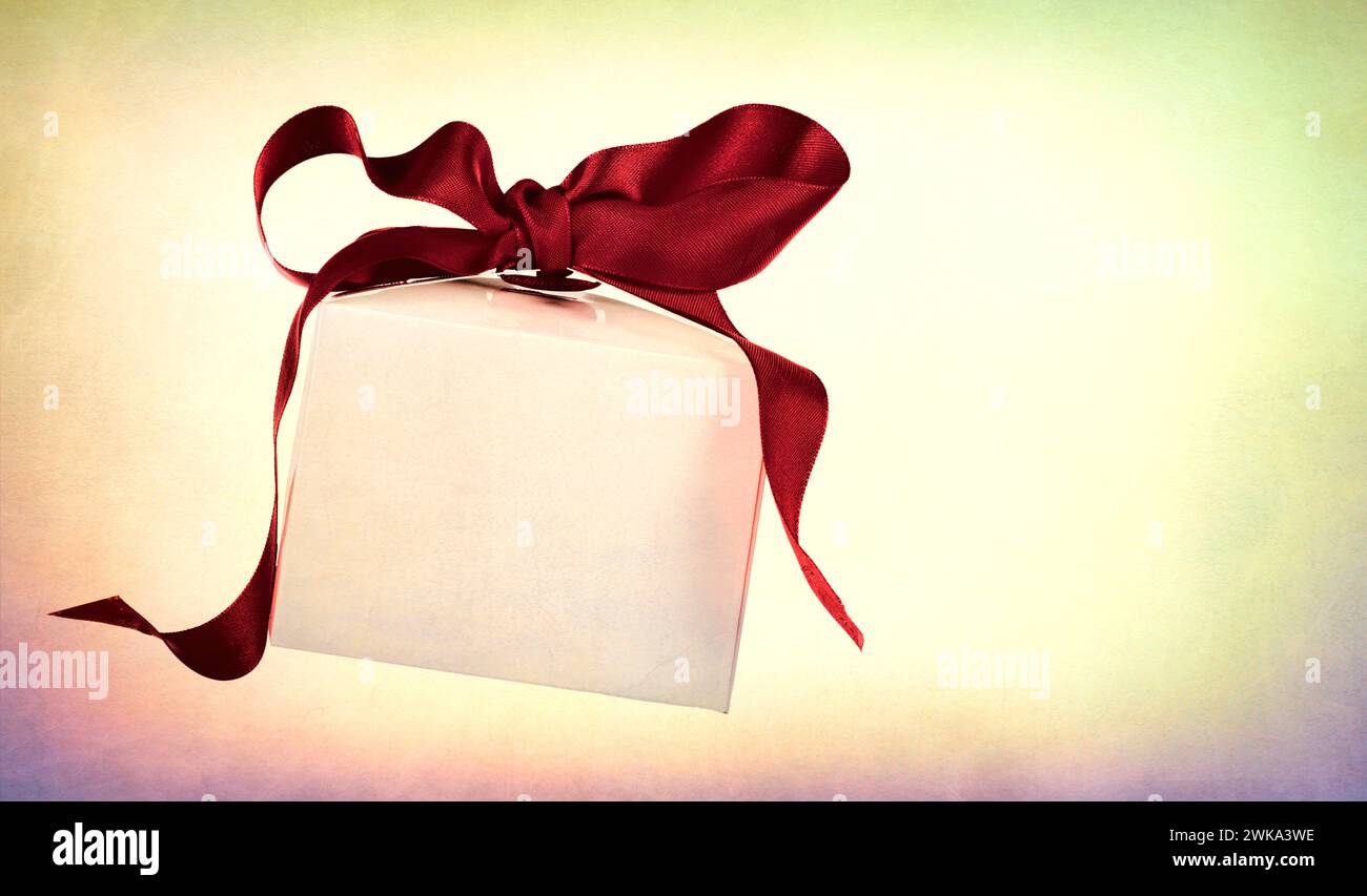 White gift box with a red bow on a vintage background with a dark ...
