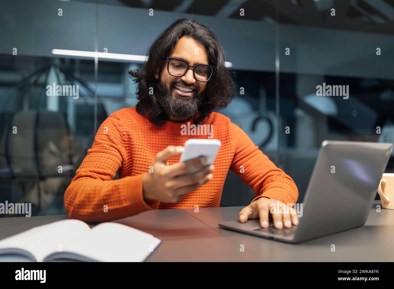 Cheerful Millennial Indian Man Using Smartphone and Laptop Stock Photo ...