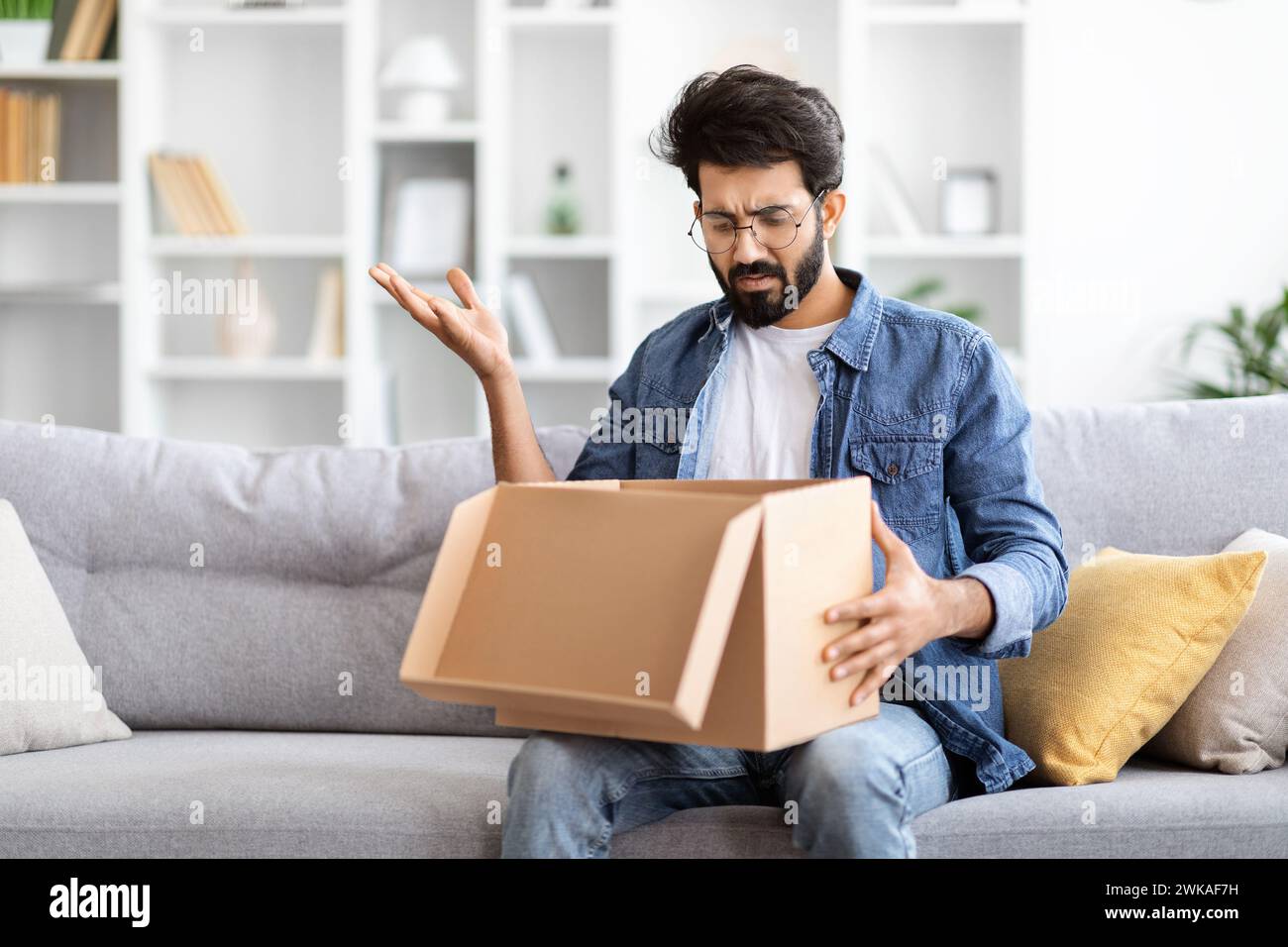 Wrong Delivery. Perplexed young indian man holding an open empty ...