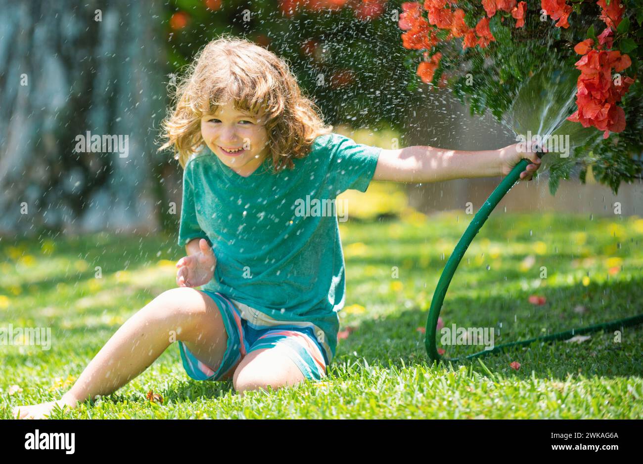 Funny kid playing with garden hose in backyard. Child having fun with ...