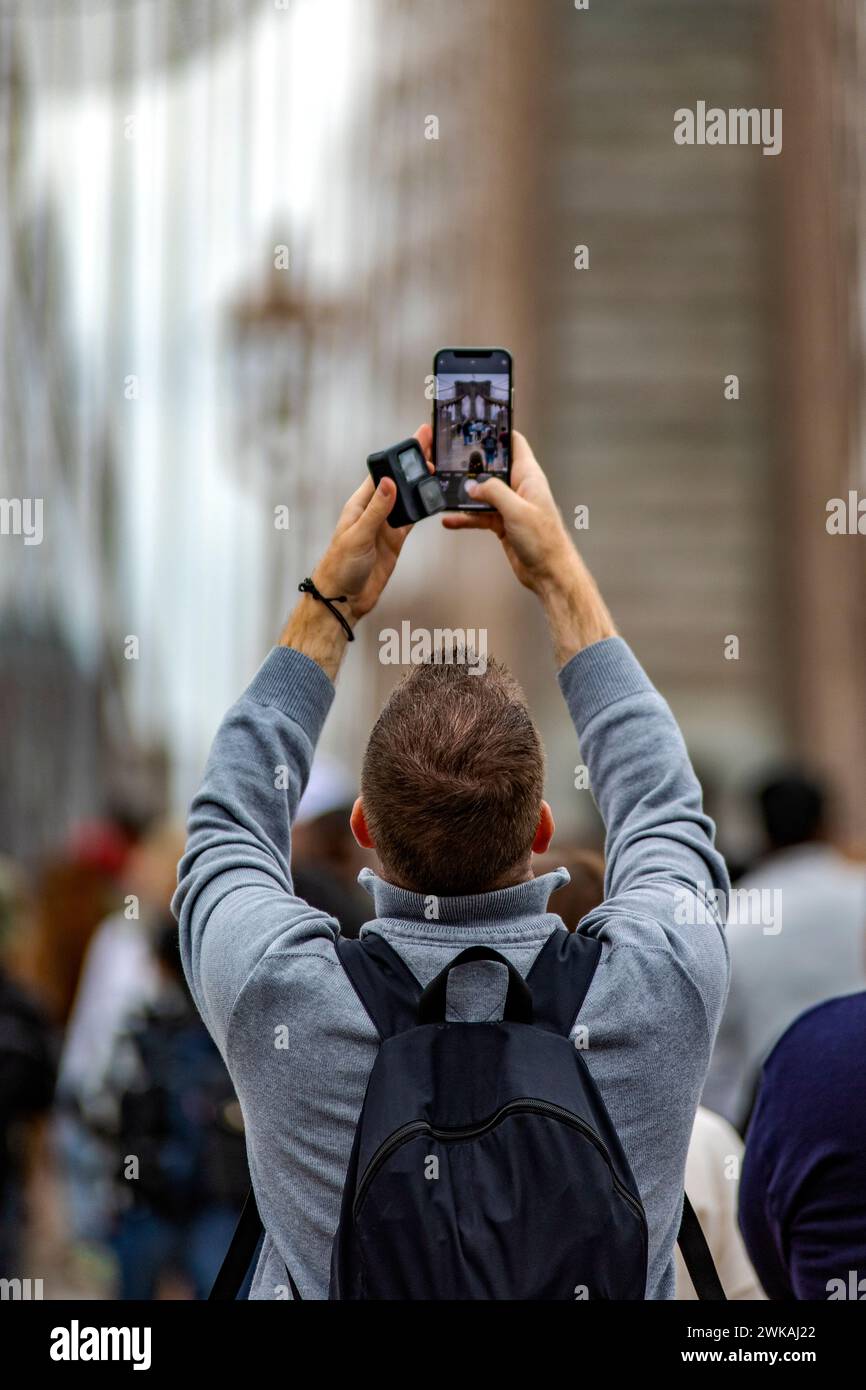 Person with mobile phone photographing the Brooklyn Bridge linking the ...