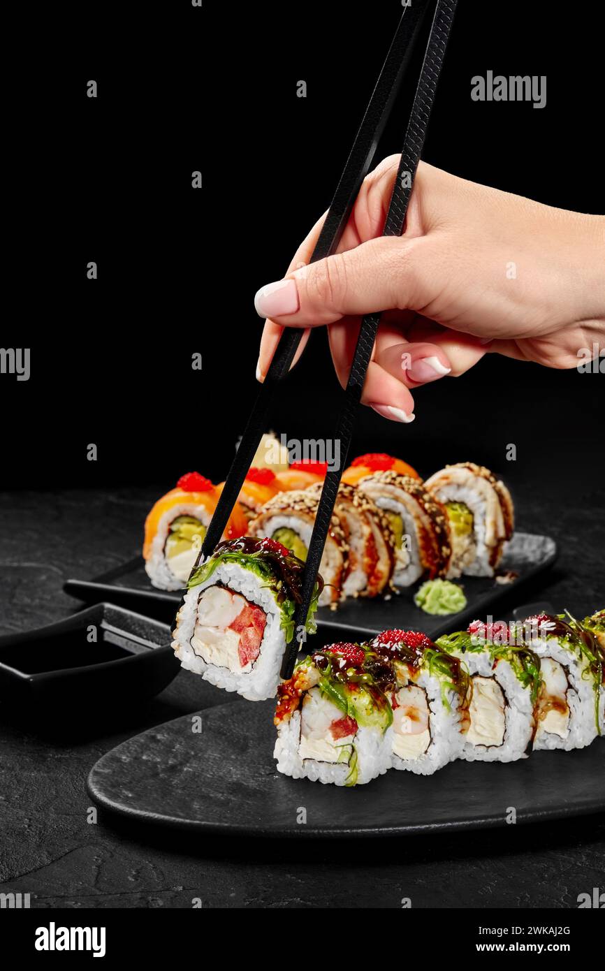 Female hand taking shrimp sushi roll from plate with chopsticks Stock Photo - Alamy