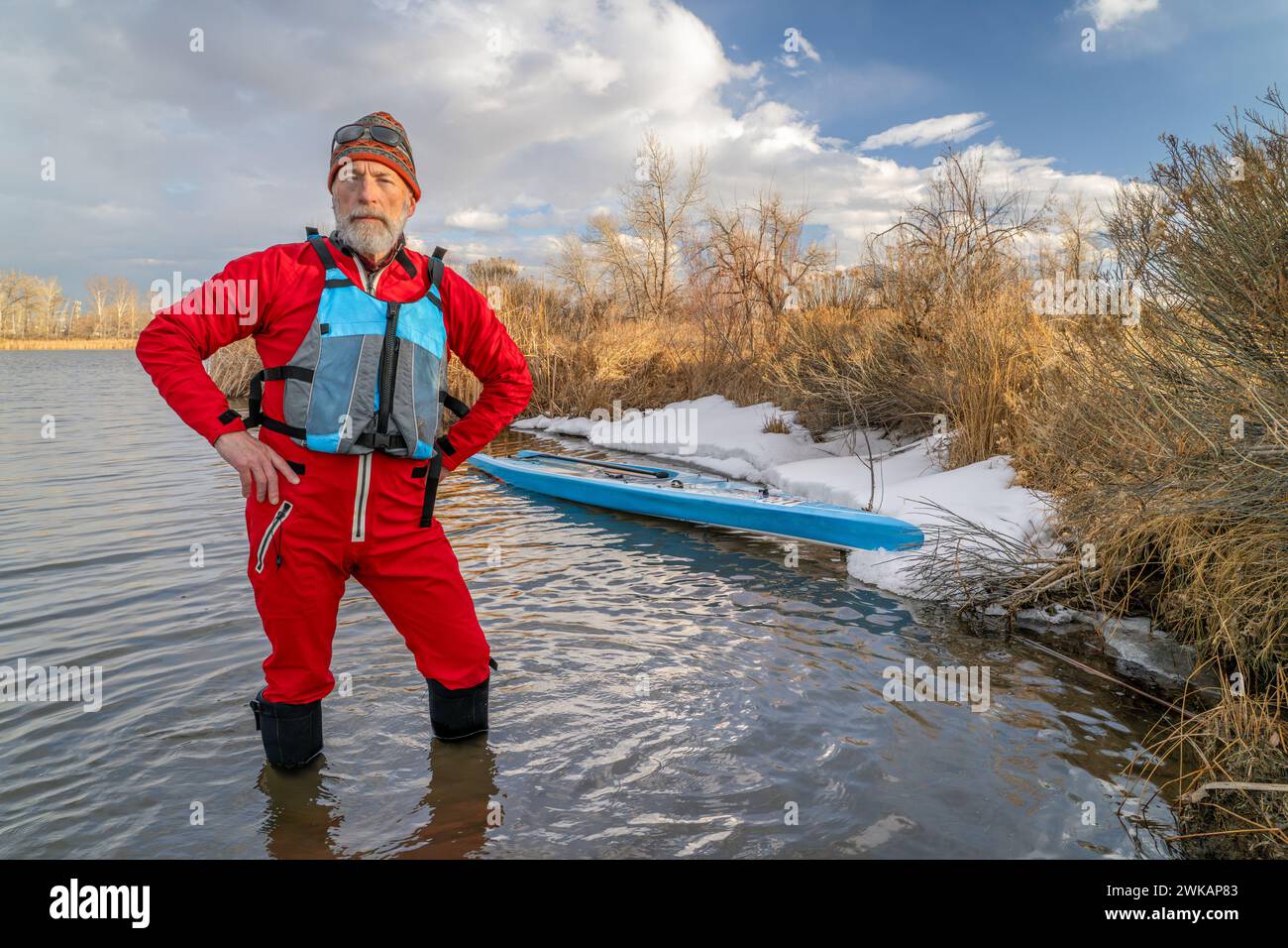 senior paddler wearing life jacket and drysuit is standing in water ...