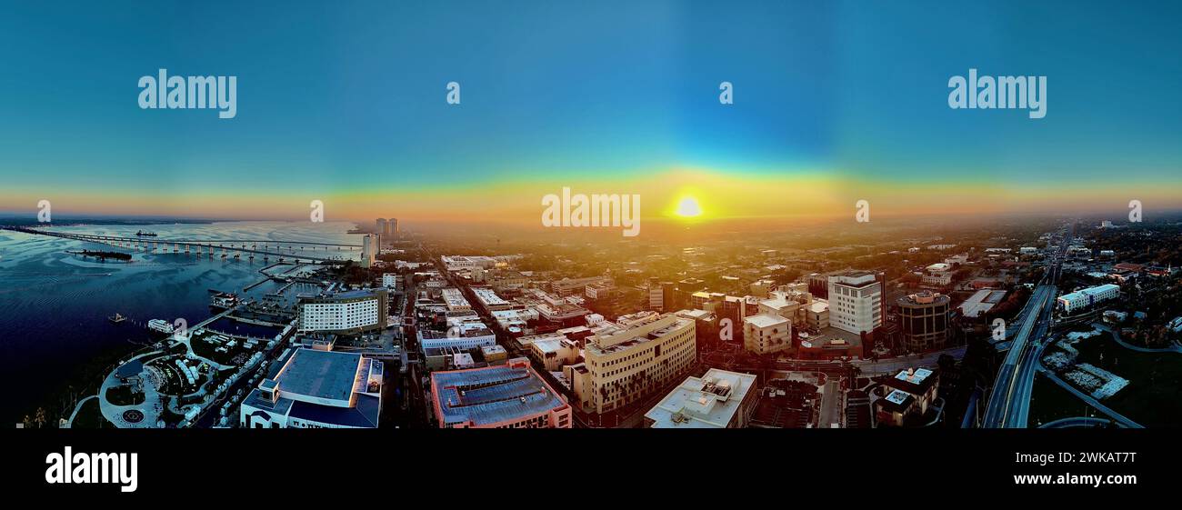 Sun setting over city buildings reflecting in water Stock Photo - Alamy