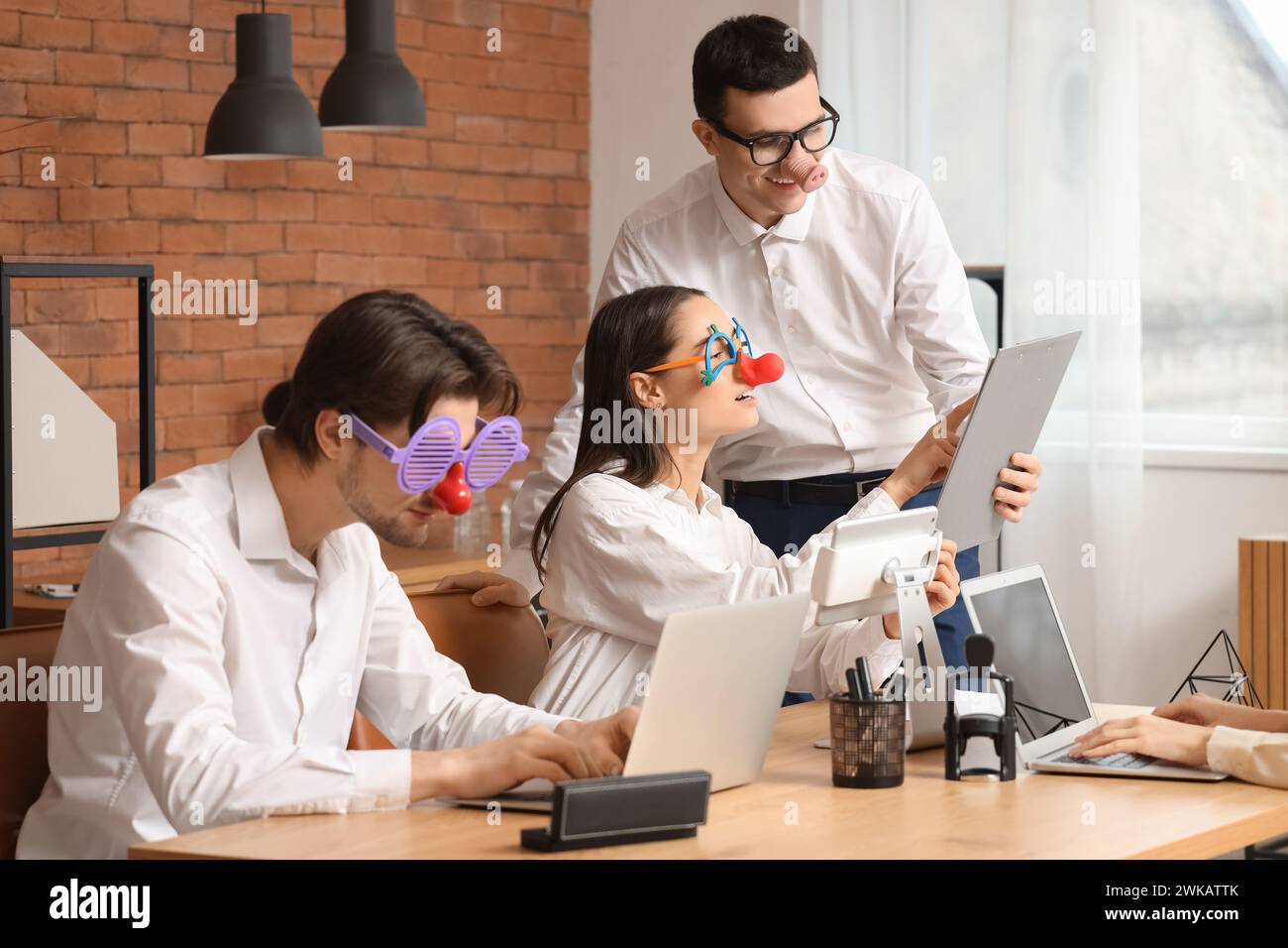 Business colleagues with funny disguise working in office. April Fools ...