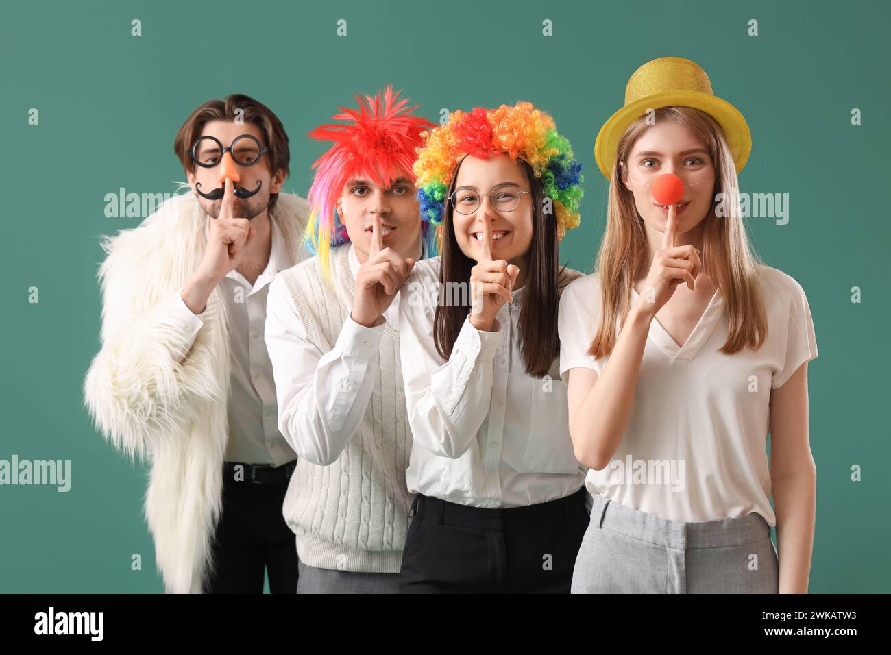 Business colleagues in funny disguise showing silence gesture on green ...