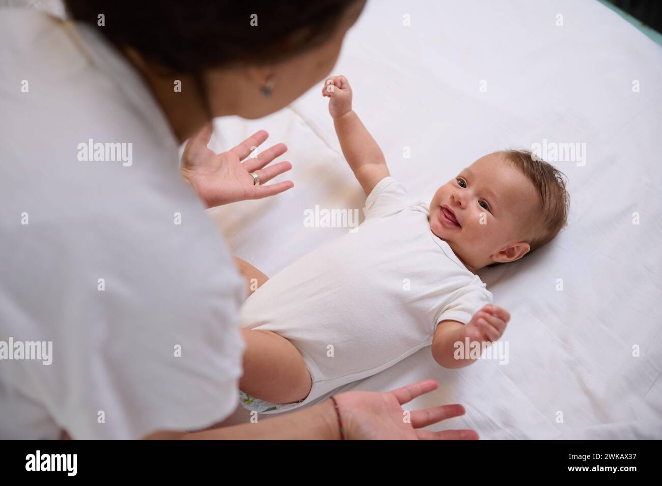 Adorable Caucasian baby boy 4 months old lying on bed, keeping his arms ...