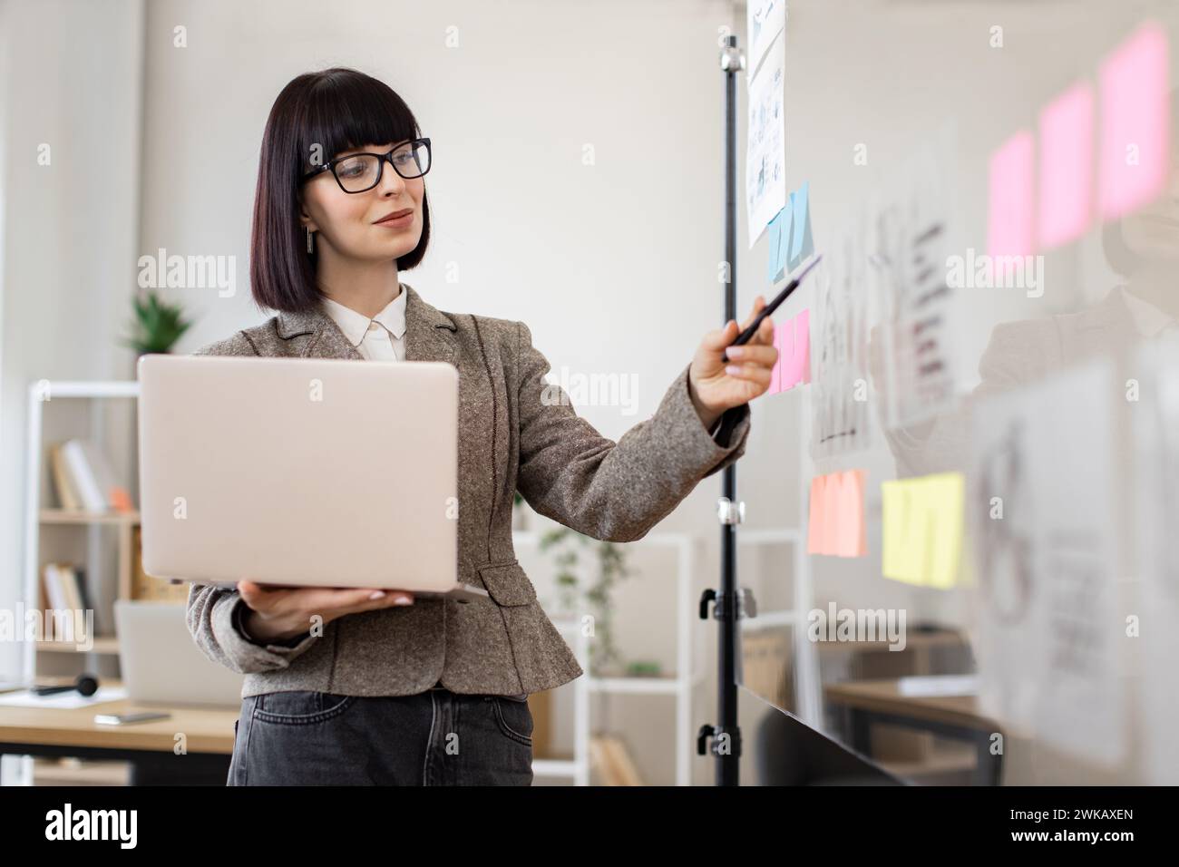 Female manager preparing for presentation, writing notes on stickers ...