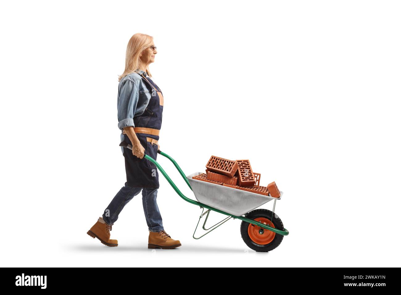 Full length profile shot of a woman pushing a wheelbarrow full of ...