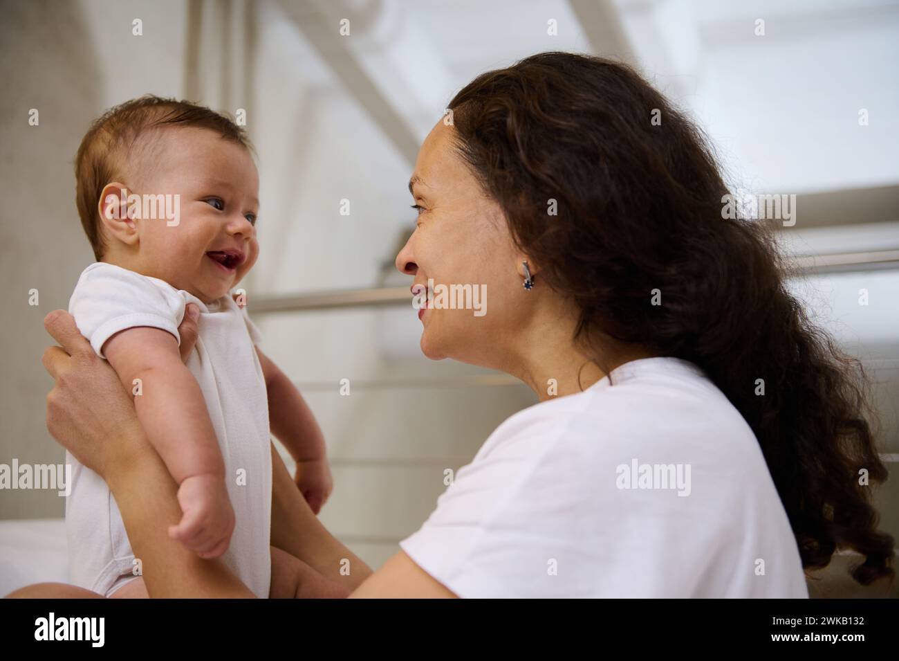 Affectionate young mom establishes emotional contact with her newborn ...