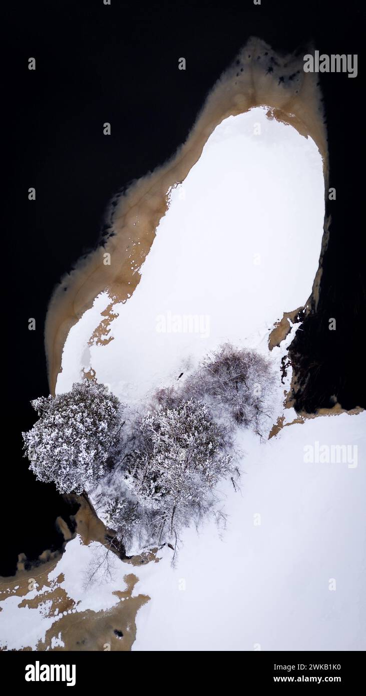 Top down view of snow covered island with frosty trees in open river ...