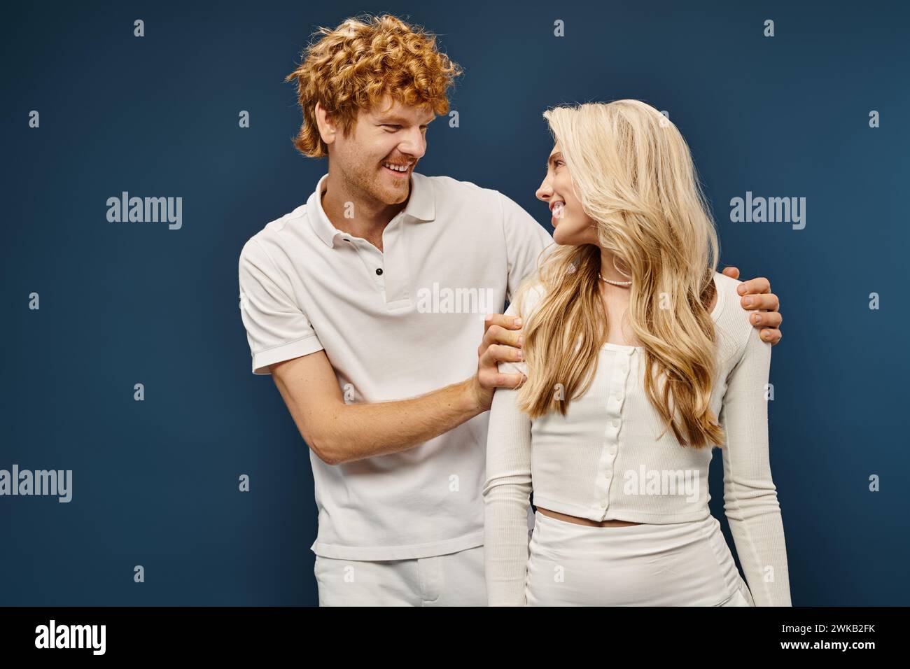 happy and wealthy couple in white outfit looking at each other on blue ...
