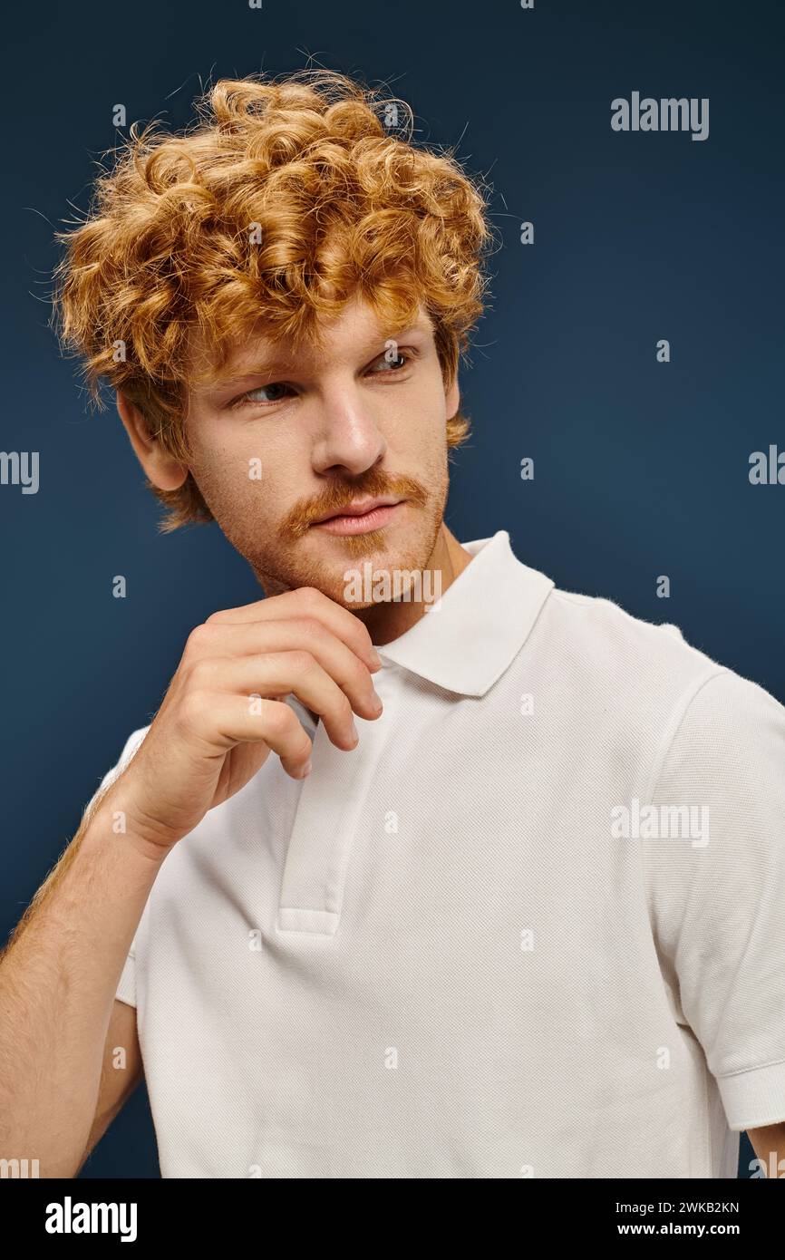 portrait of trendy redhead man in white polo t-shirt looking away on ...