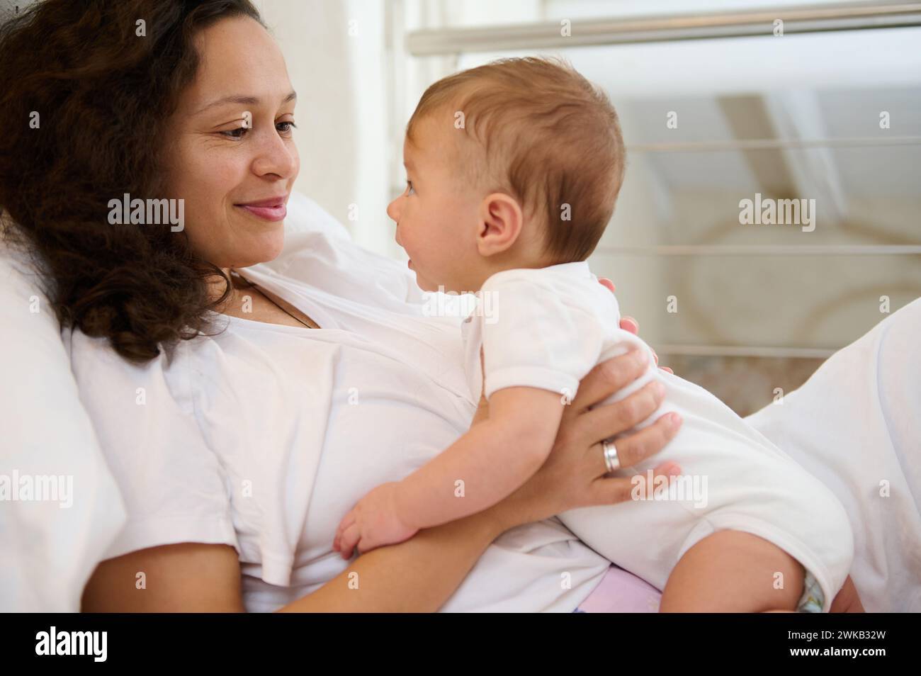 Newborn baby in tender embrace of mother. Happy delightful young ...