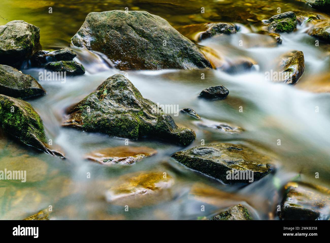 Long exposure image of water streaming around the rocks in a creek in ...