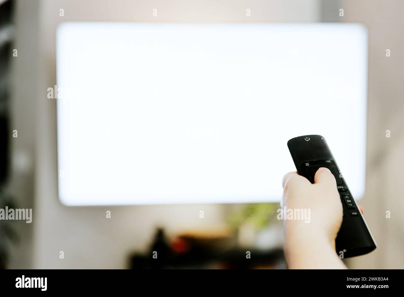 Hand holding remote control pointing to TV. Person watching smart ...