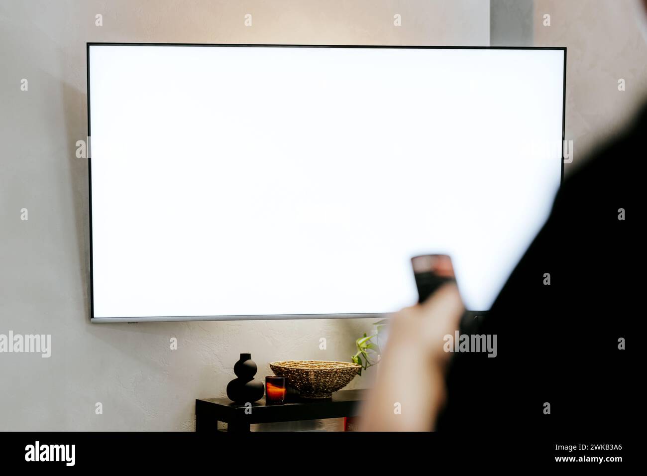 Hand holding remote control pointing to TV. Person watching smart ...