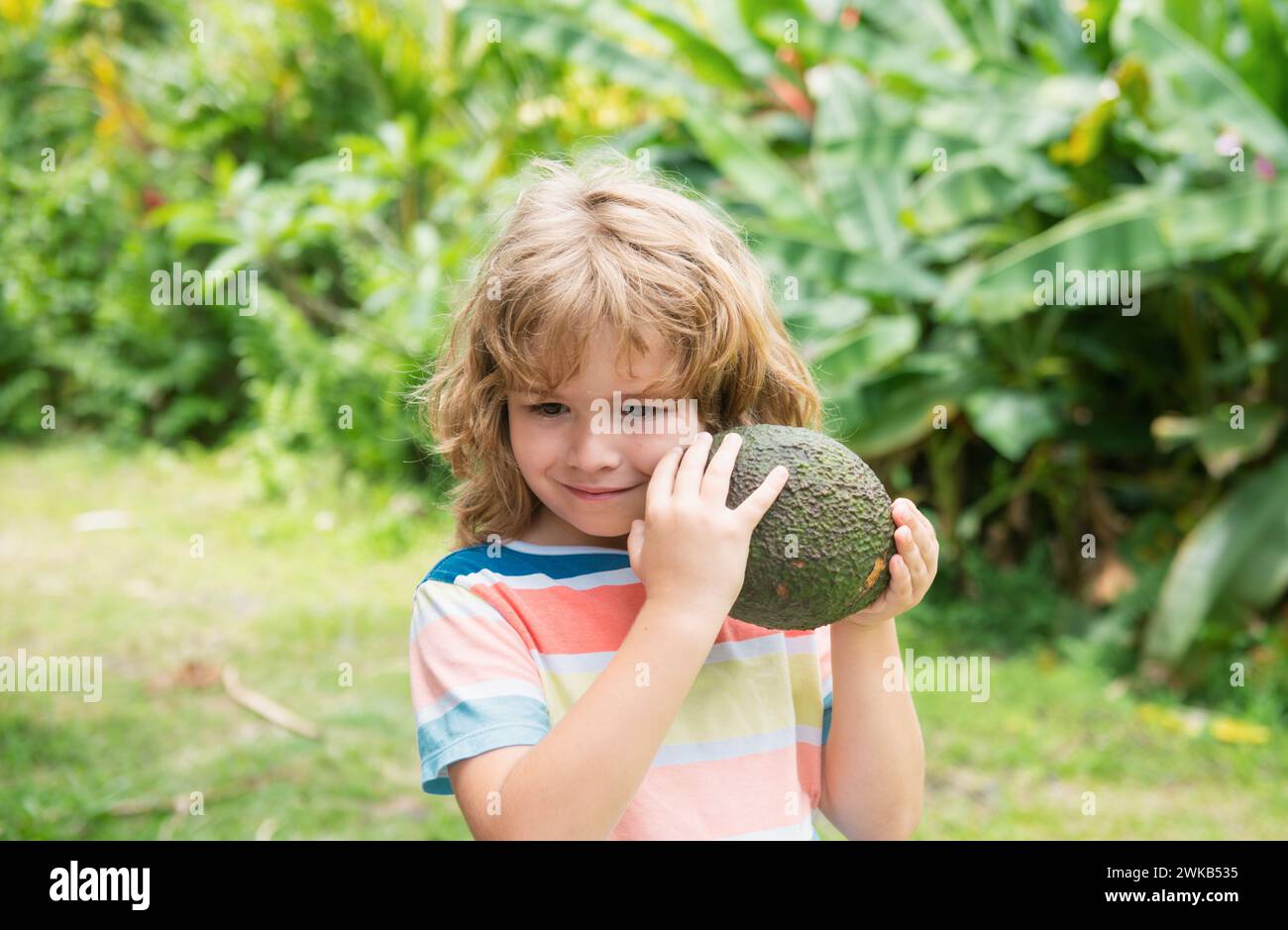 Kid eating and enjoying an avocado on a nature background. Healthy food ...