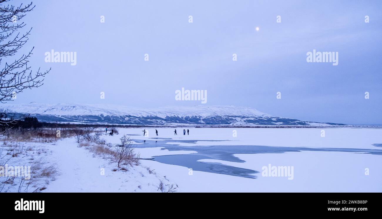 People skating on the ice at Laugarvatn, Iceland, as a full moon comes ...