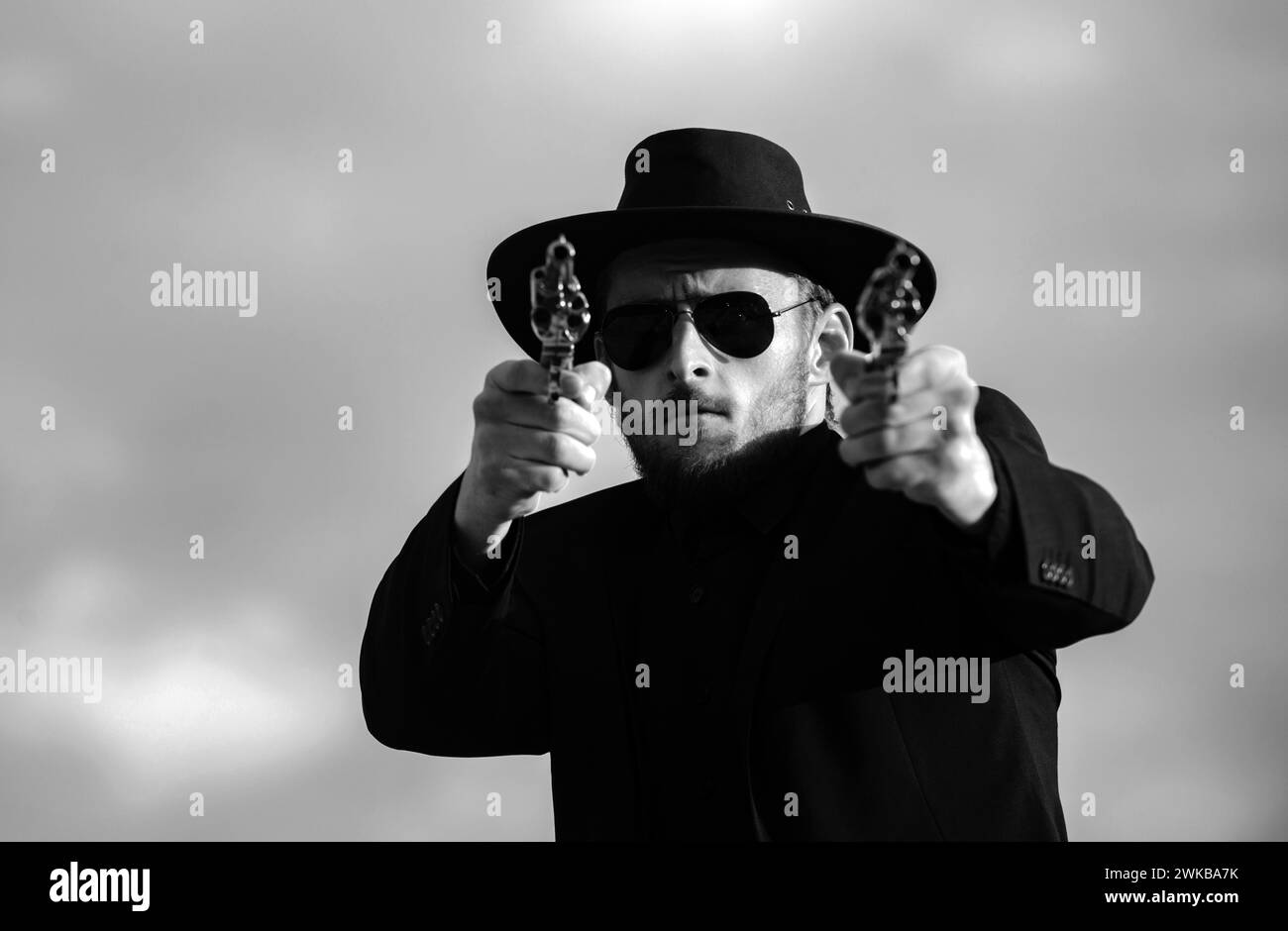 Sheriff in black suit and cowboy hat shooting gun, close up western ...