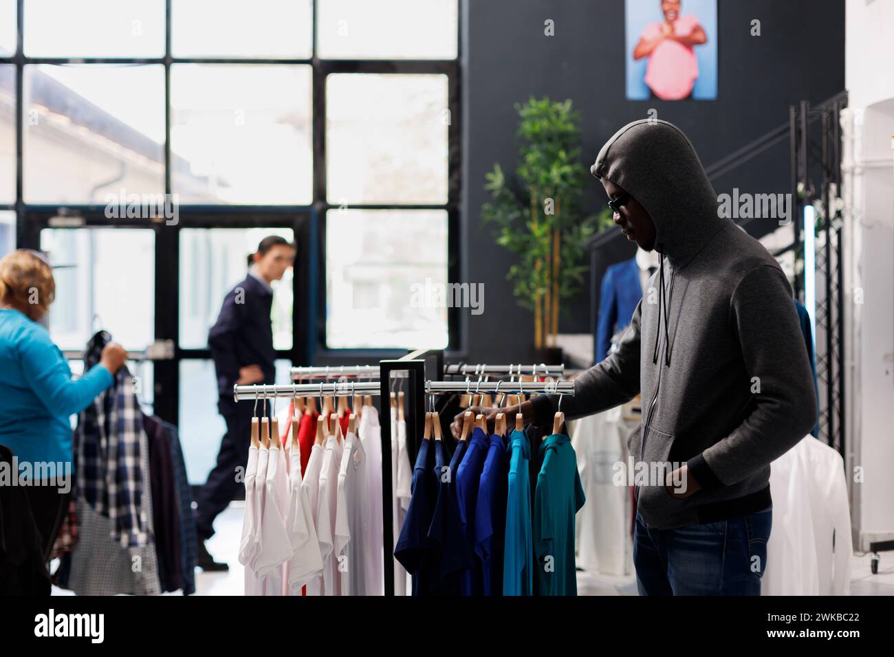 African american robber trying to steal casual wear, looking around to ...