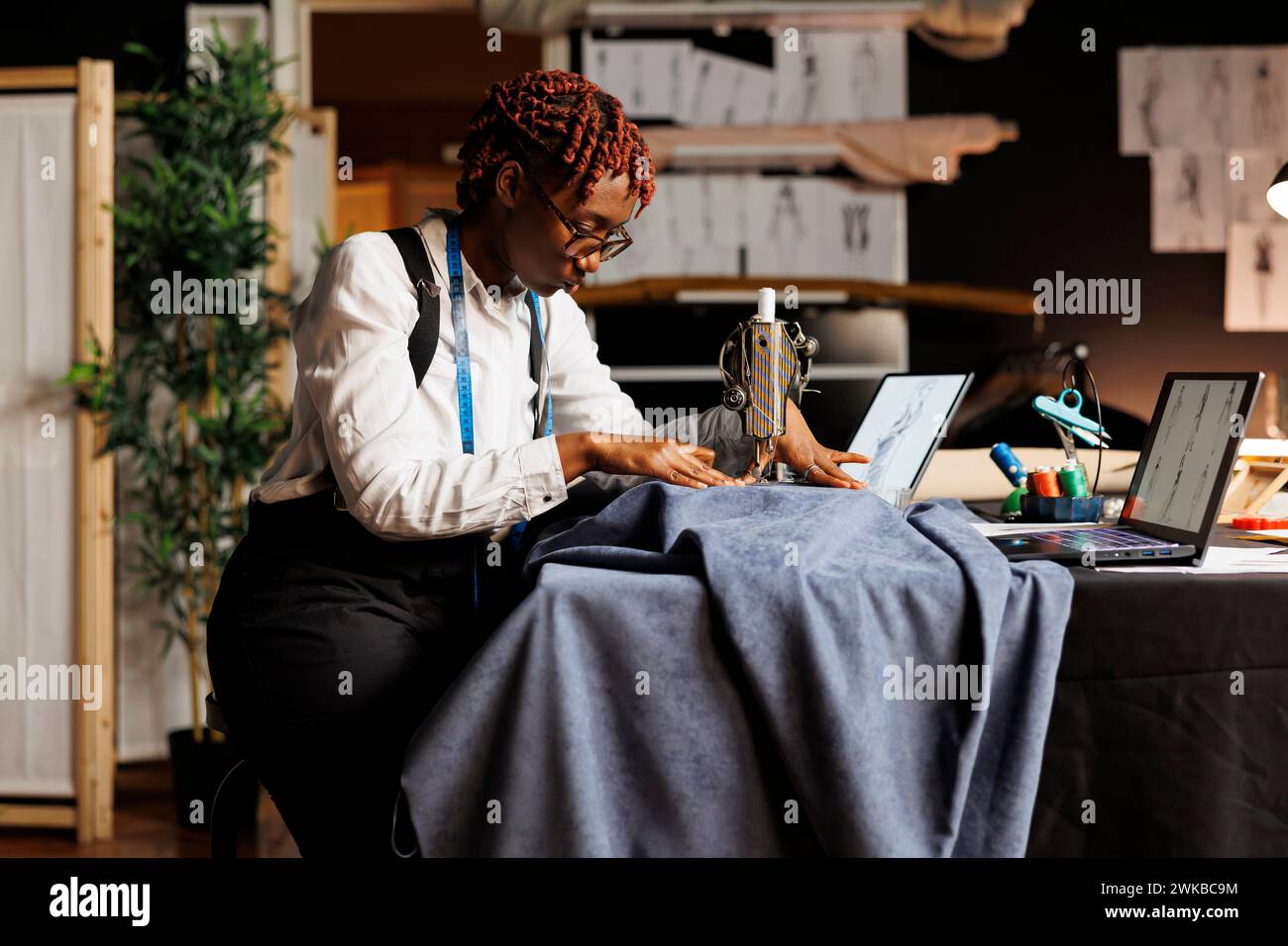 Creative tailor sewing textile garment for upcoming customer bespoke ...