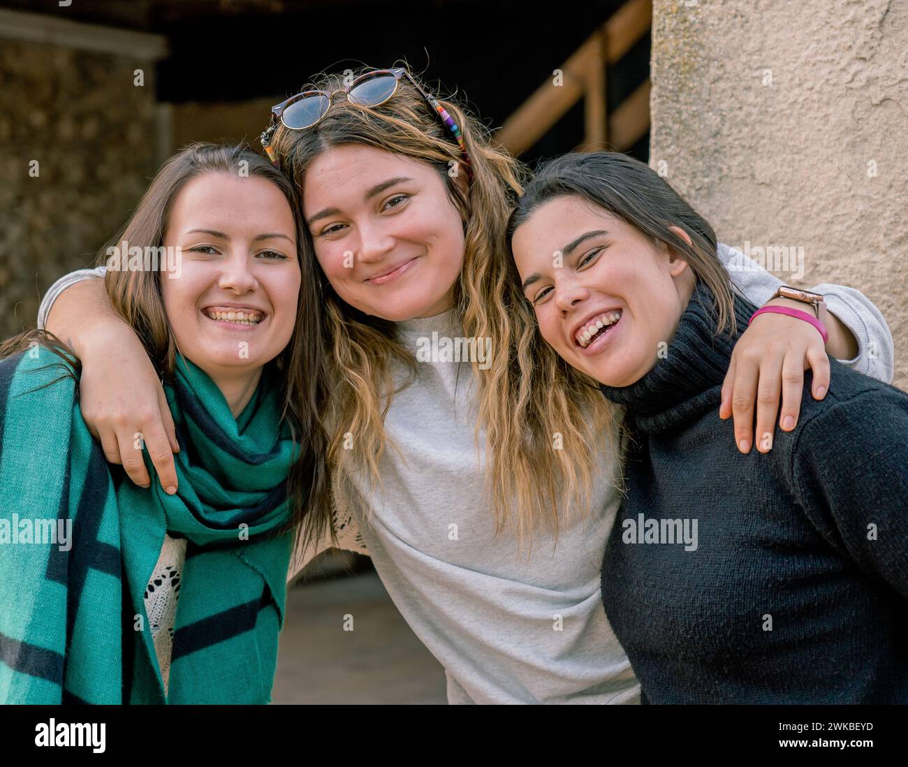 Three women leaning together smiling and looking at the camera ...