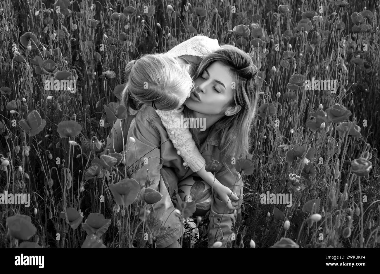 Mother with daughter outdoor in poppy field. Mom hugs lovely child on ...