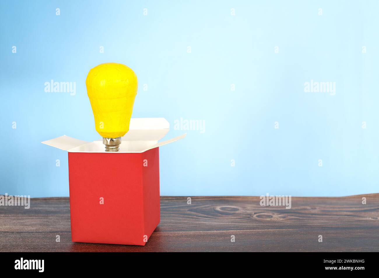 Yellow light bulb coming out of a box. Think outside the box concept ...