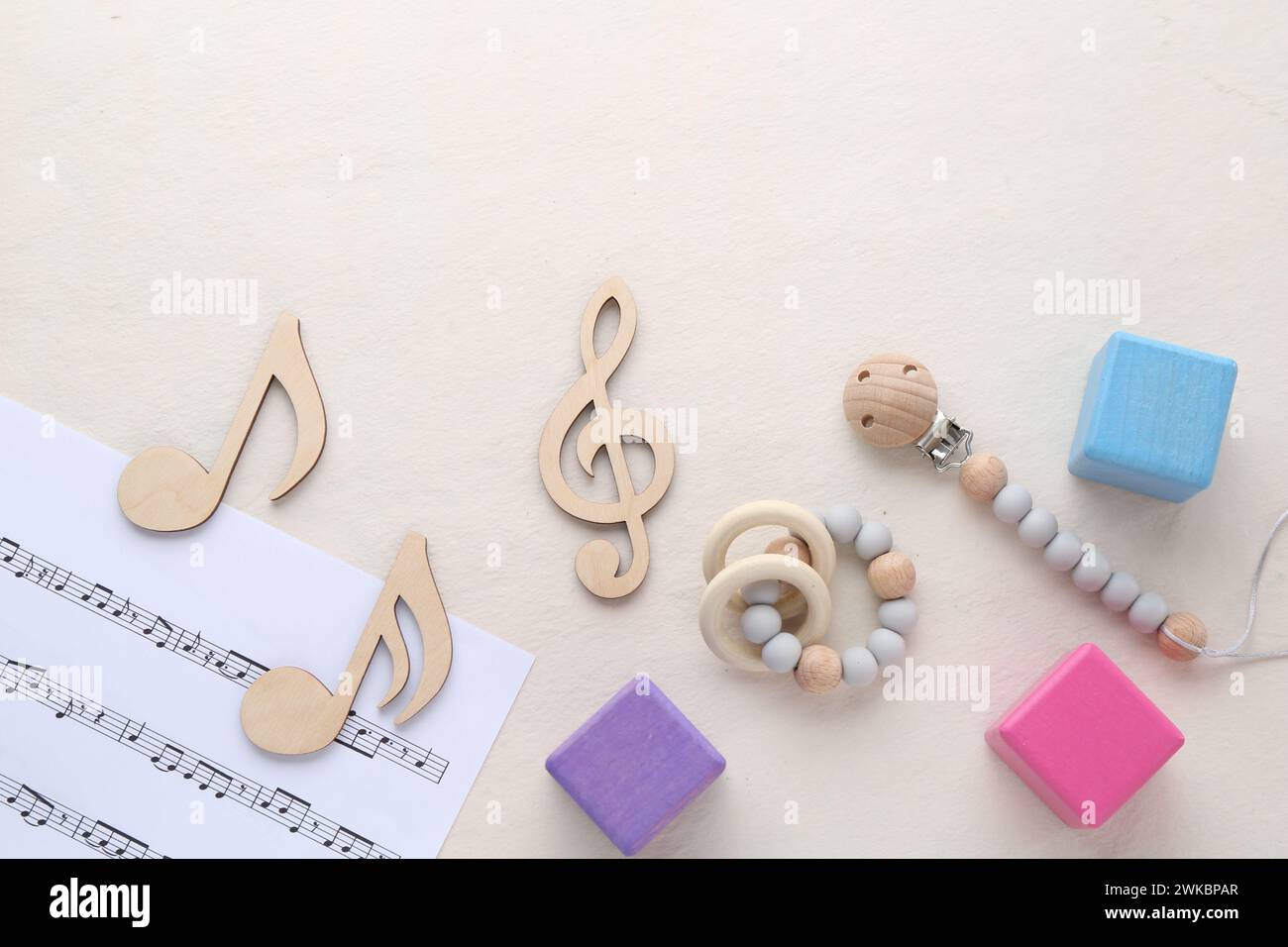 Wooden notes, music sheet and toys on beige background, flat lay with ...