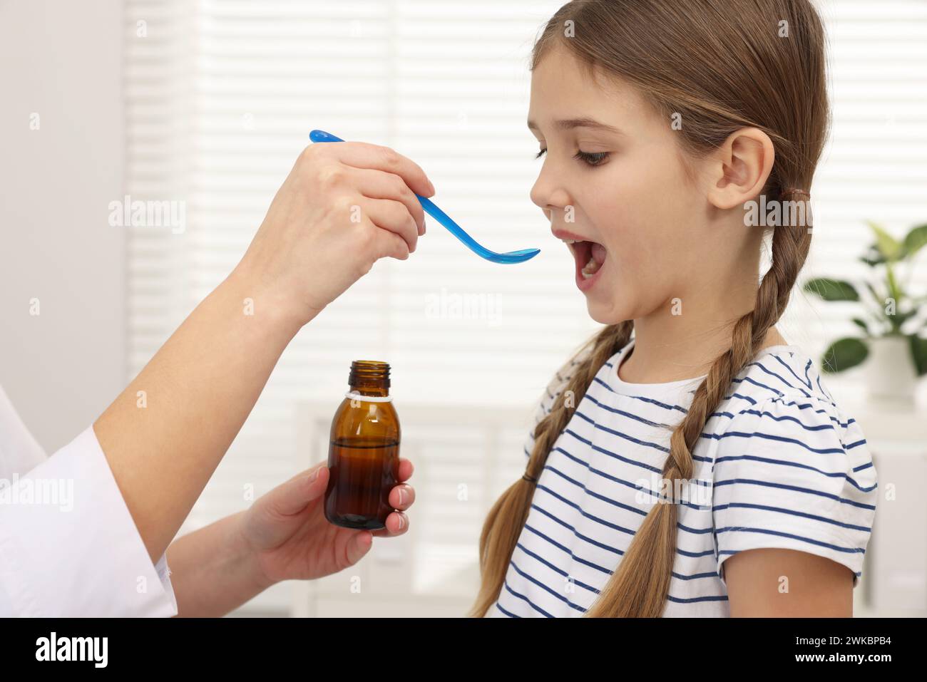 Doctor giving cough syrup to girl in clinic Stock Photo - Alamy