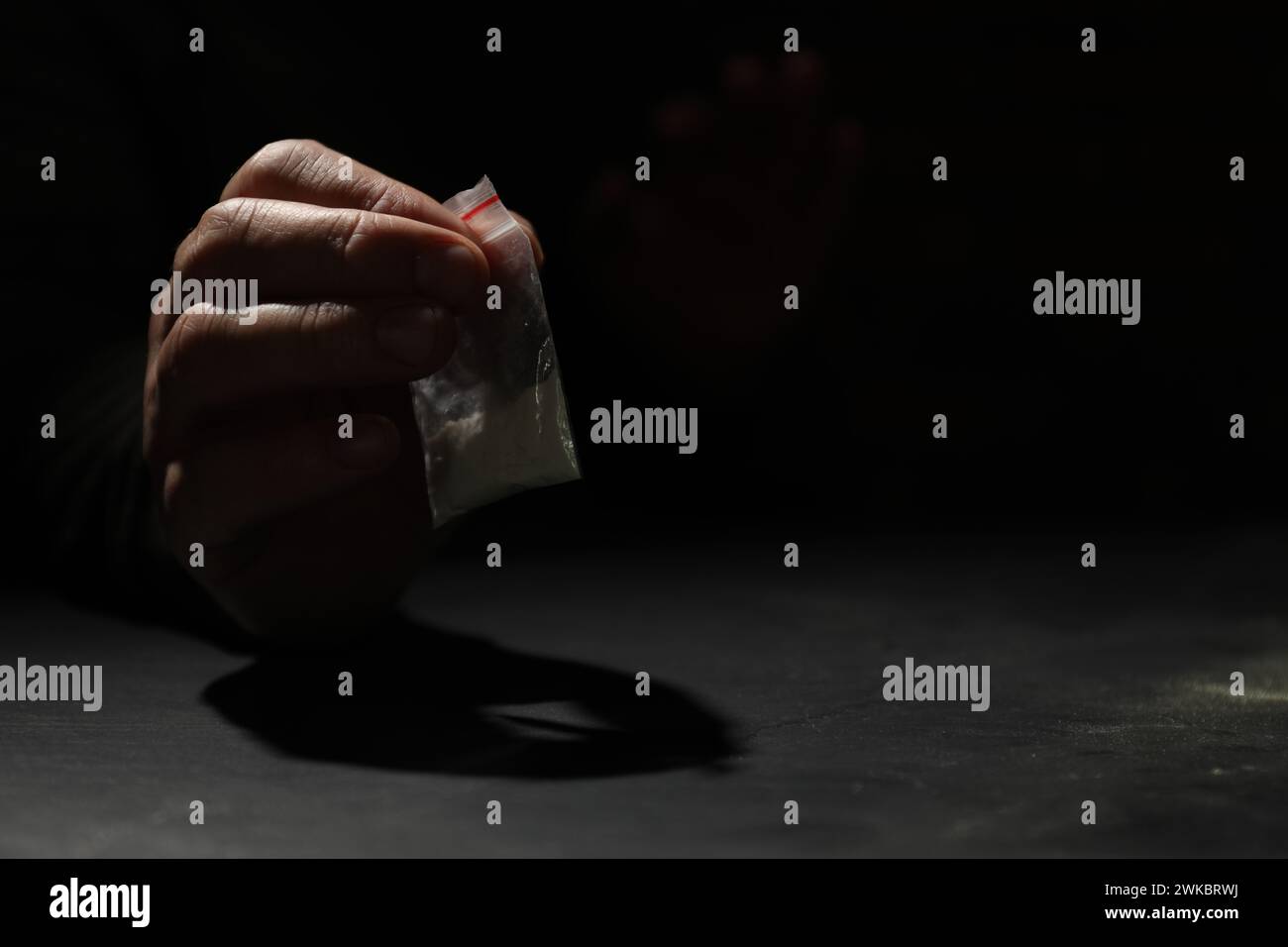 Addicted man with plastic bag of hard drug at grey table, closeup ...