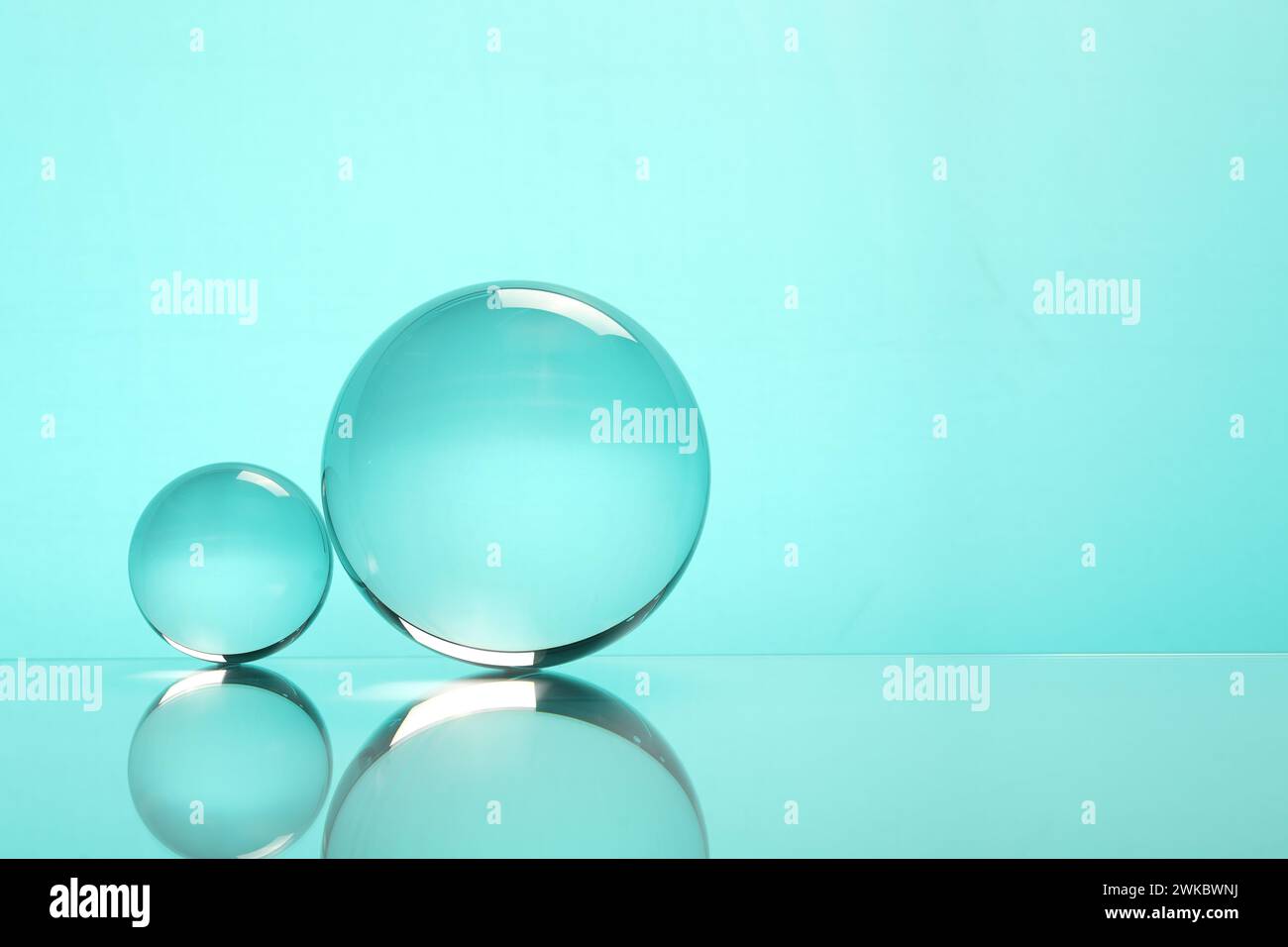 Transparent glass balls on mirror surface against turquoise background ...