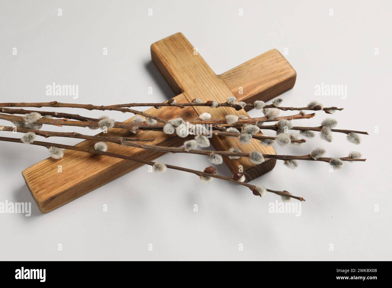 Wooden cross and willow branches on light grey background. Easter ...