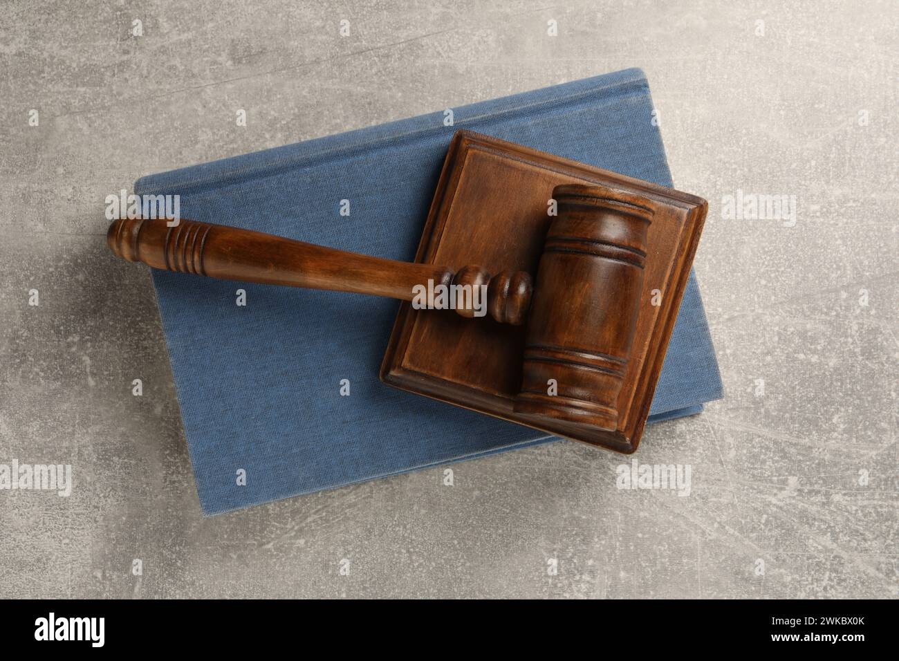 Wooden gavel, sound block and book on grey textured table, top view ...