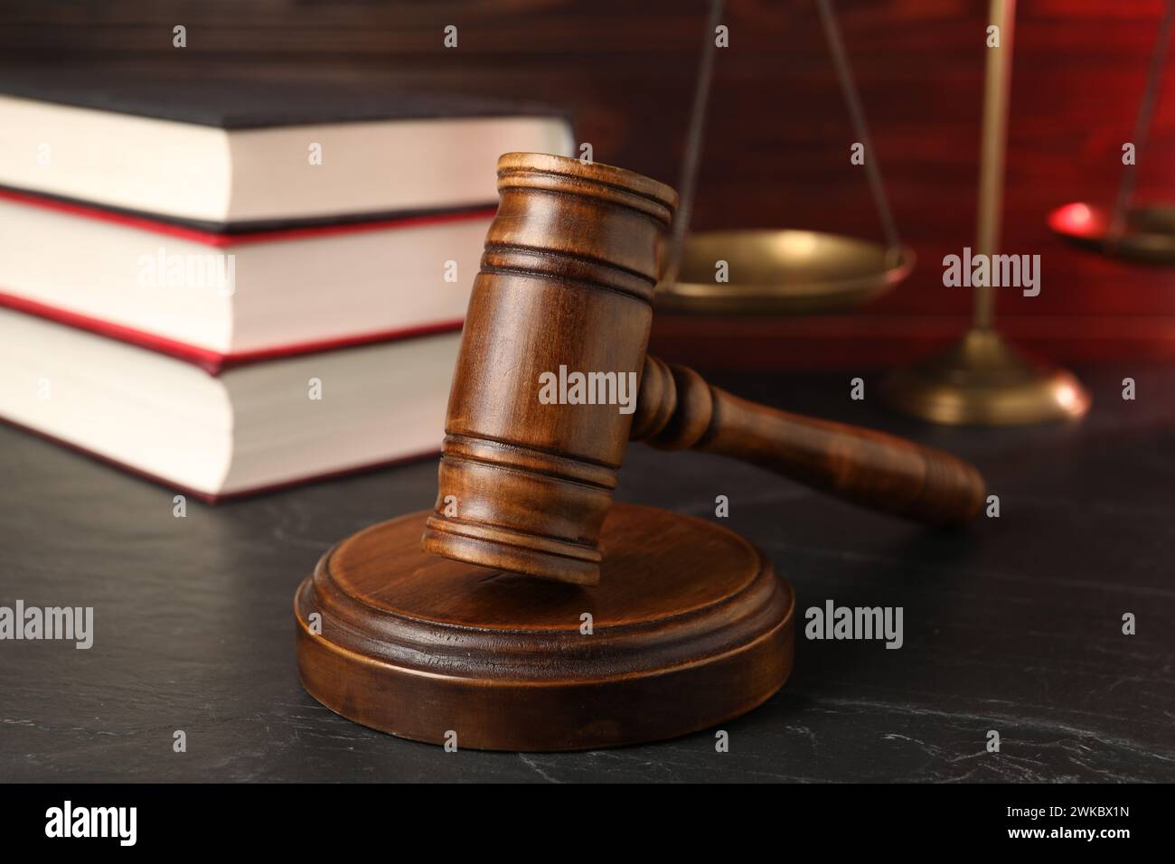 Wooden gavel, scales and stack of books on dark textured table, closeup ...